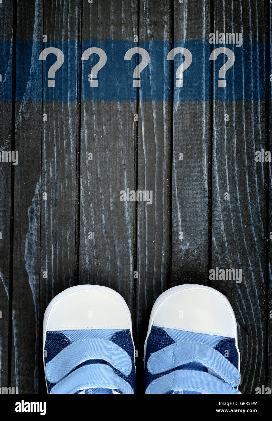 Question marks message and kid shoes on wooden floor Stock Photo - Alamy
