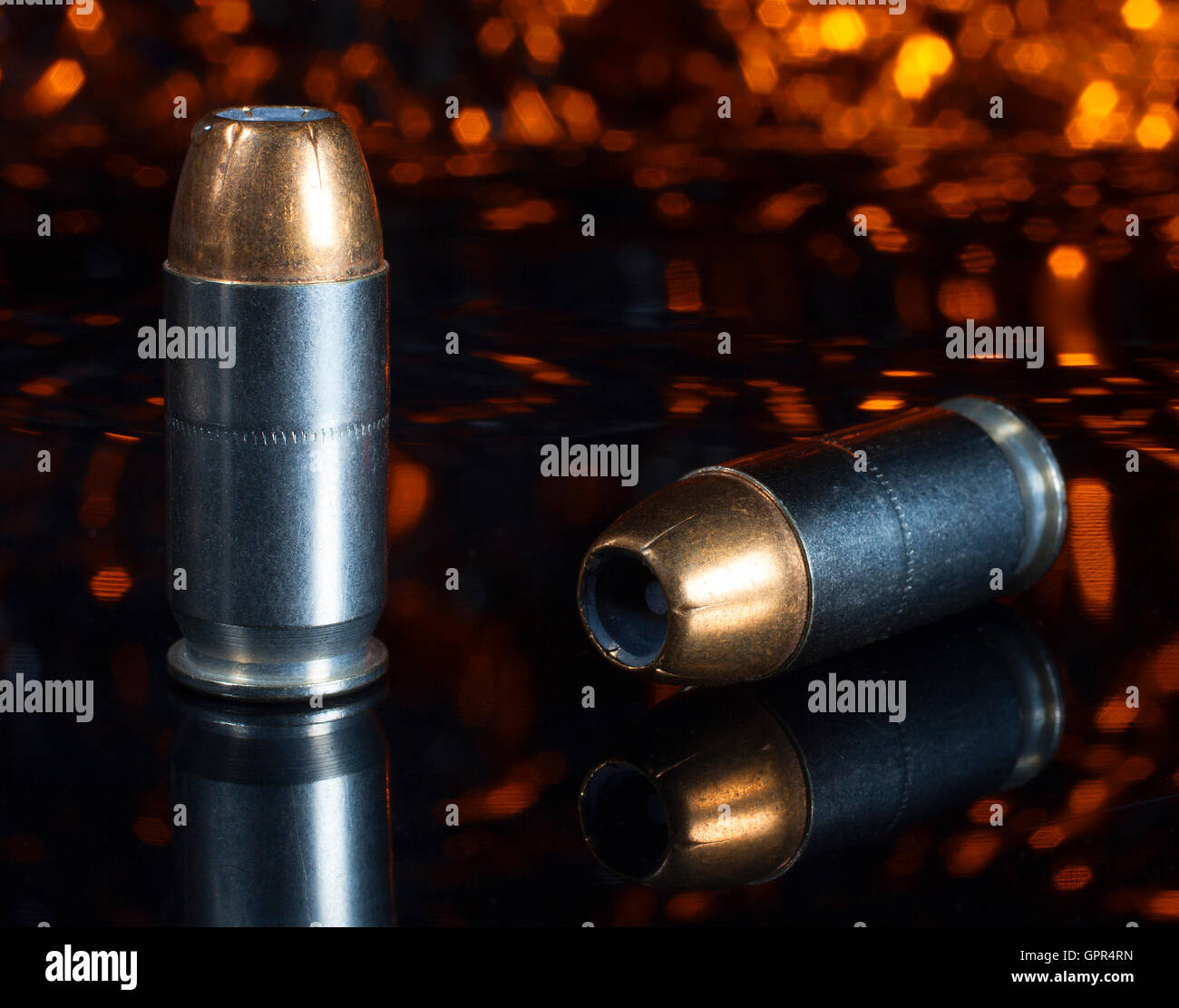Two hollowpoint bullets in a dark setting with orange behind Stock ...
