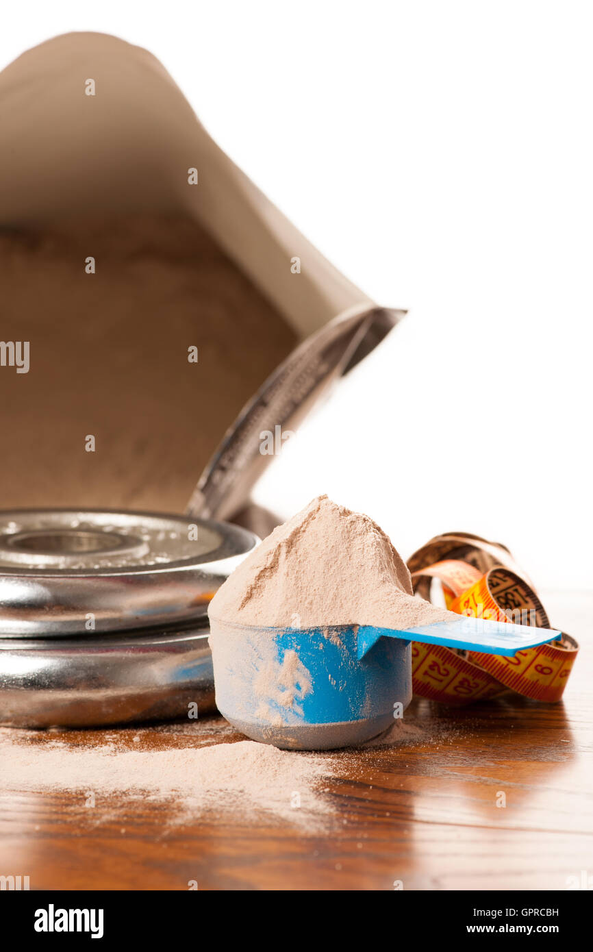 Whey protein powder in measuring scoop, meter tape and dumbbell on ...