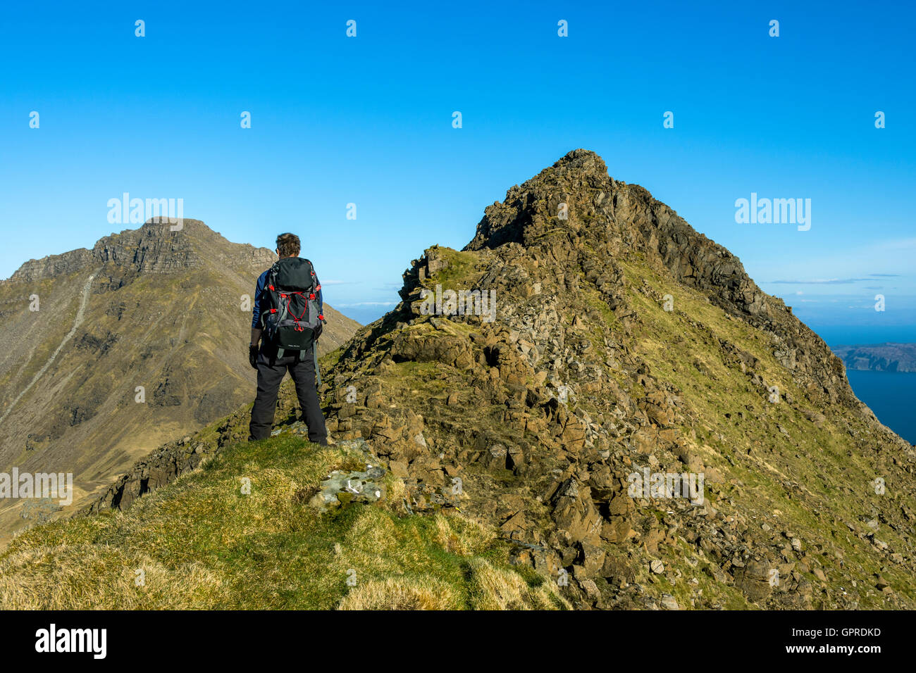 Walker on the summit ridge of Trollabhal in the Rum Cuillin hills, Isle ...