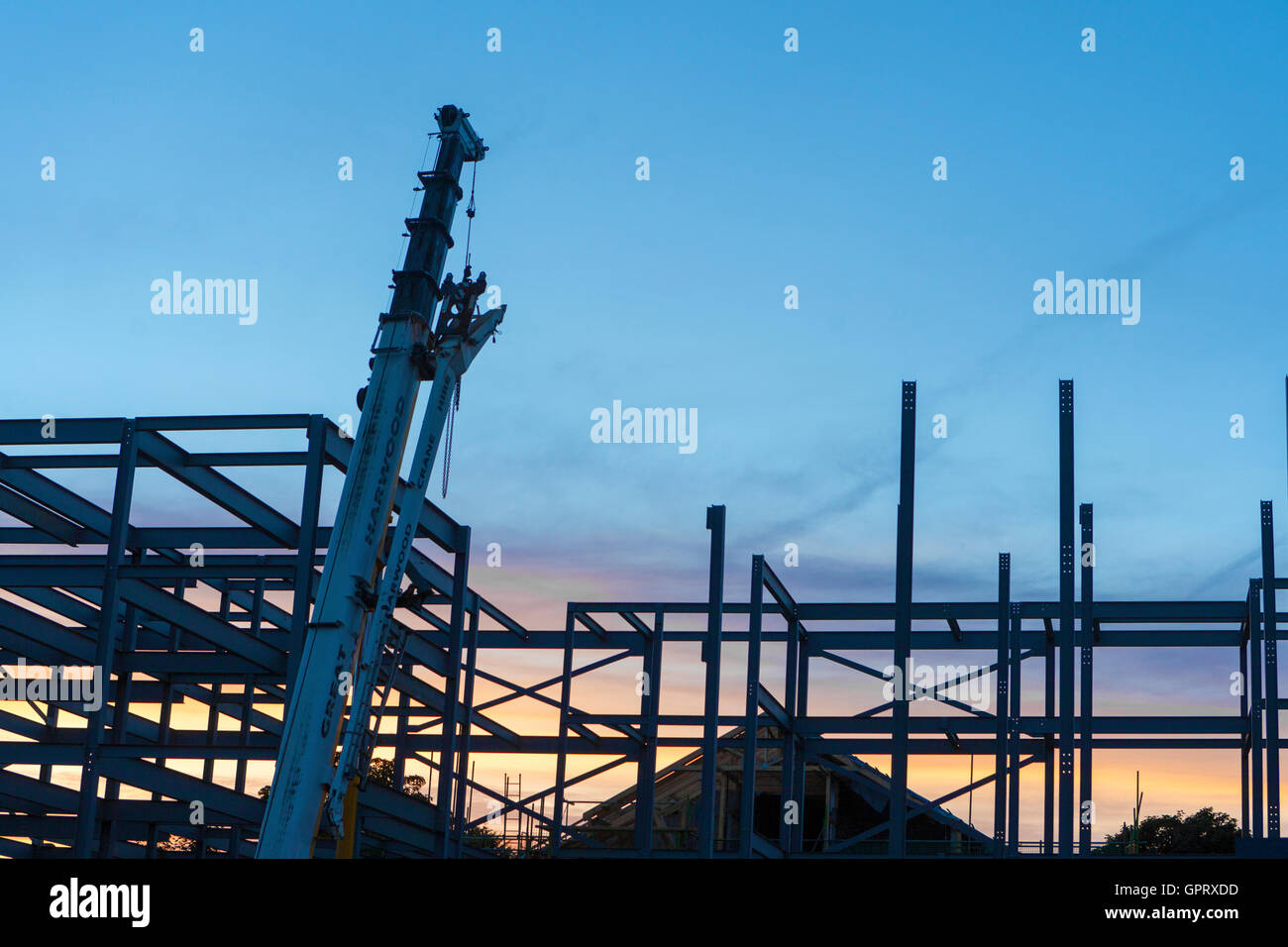 A construction site with steel erection silhouetted against a sunset ...