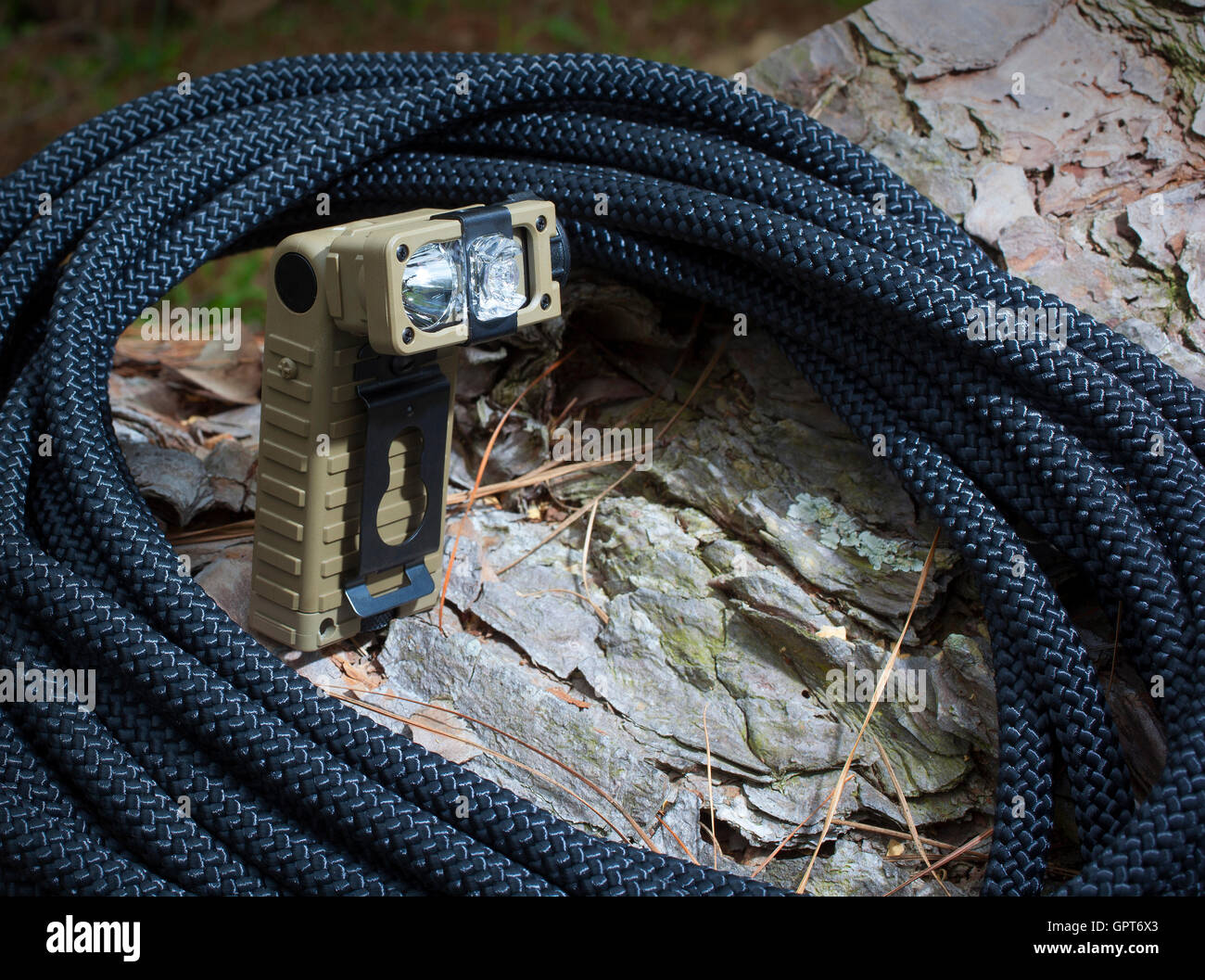 Black rope around a tan flashlight that can have its head rotate while ...