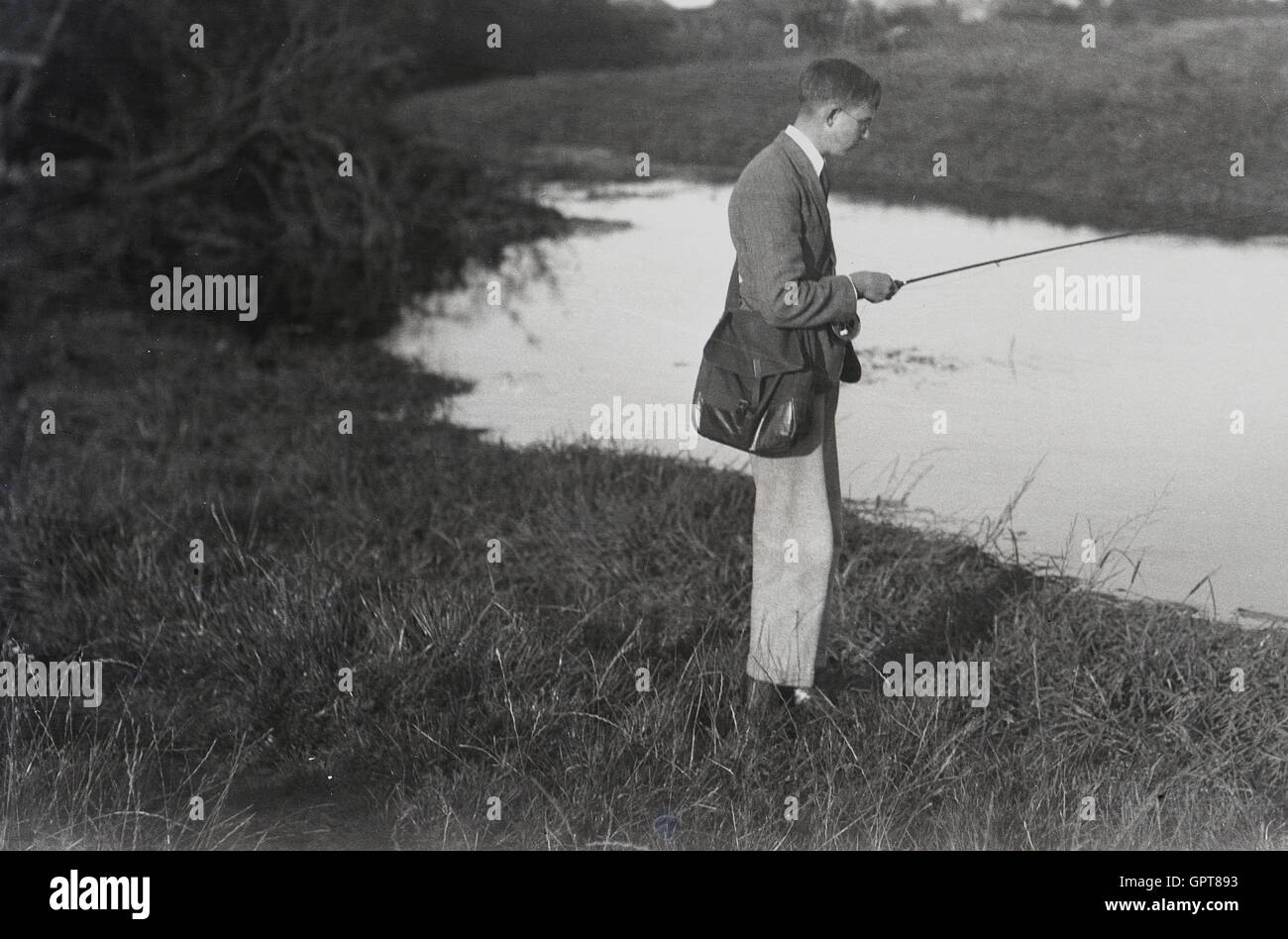 1930s, historical, young man with satchel fishing beside the River ...
