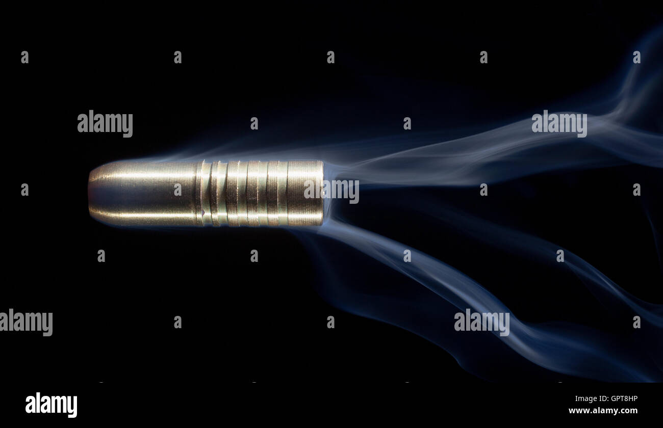 Big copper bullet with smoke trailing behind on a black background ...