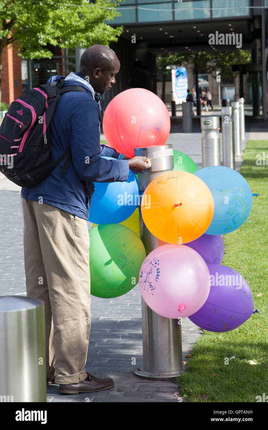 Enterprising Balloon Seller inflating his balloons to sell, as Summer ...