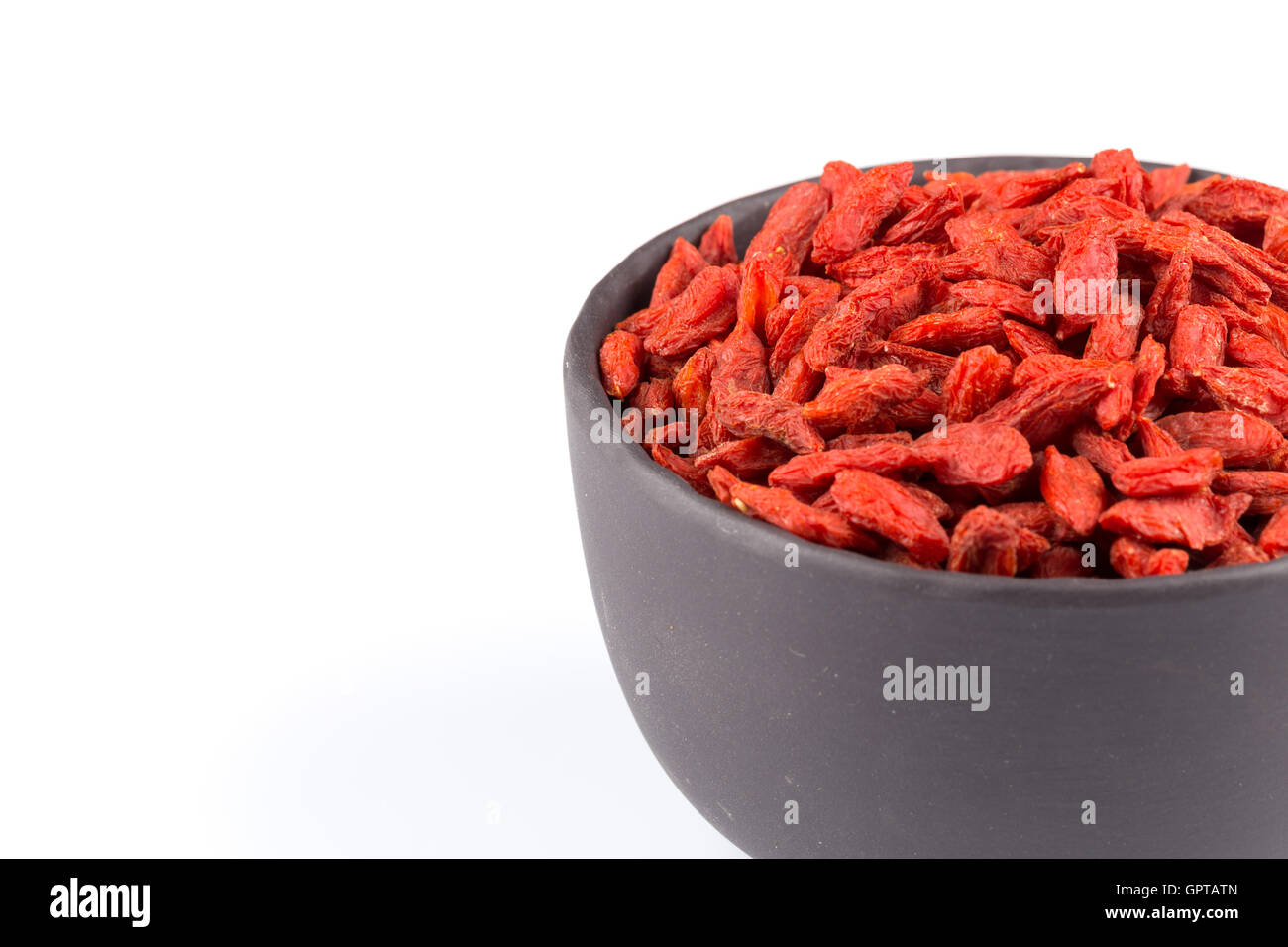 Chinese goji berries in dark stone bowl close up on white background ...