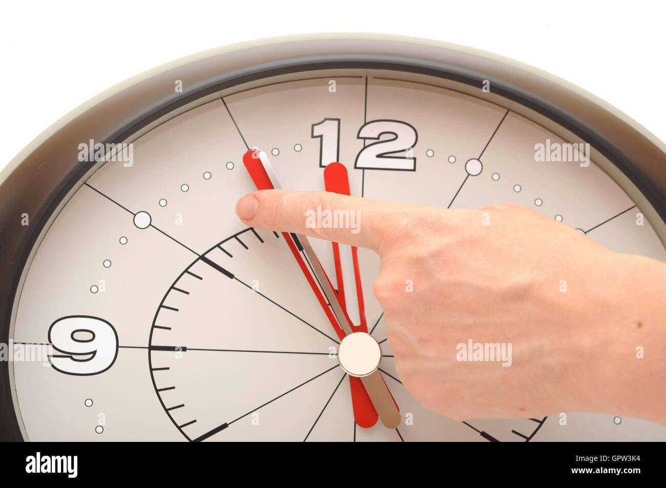 Wall clock showing five minutes to twelve and a hand bringing ar Stock ...