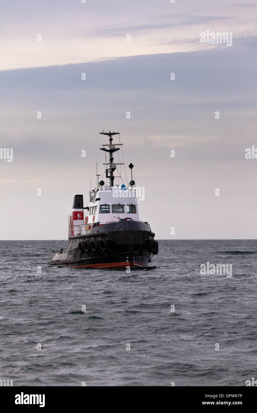 Tugboat floating in wait on calm ocean at anchor Stock Photo - Alamy