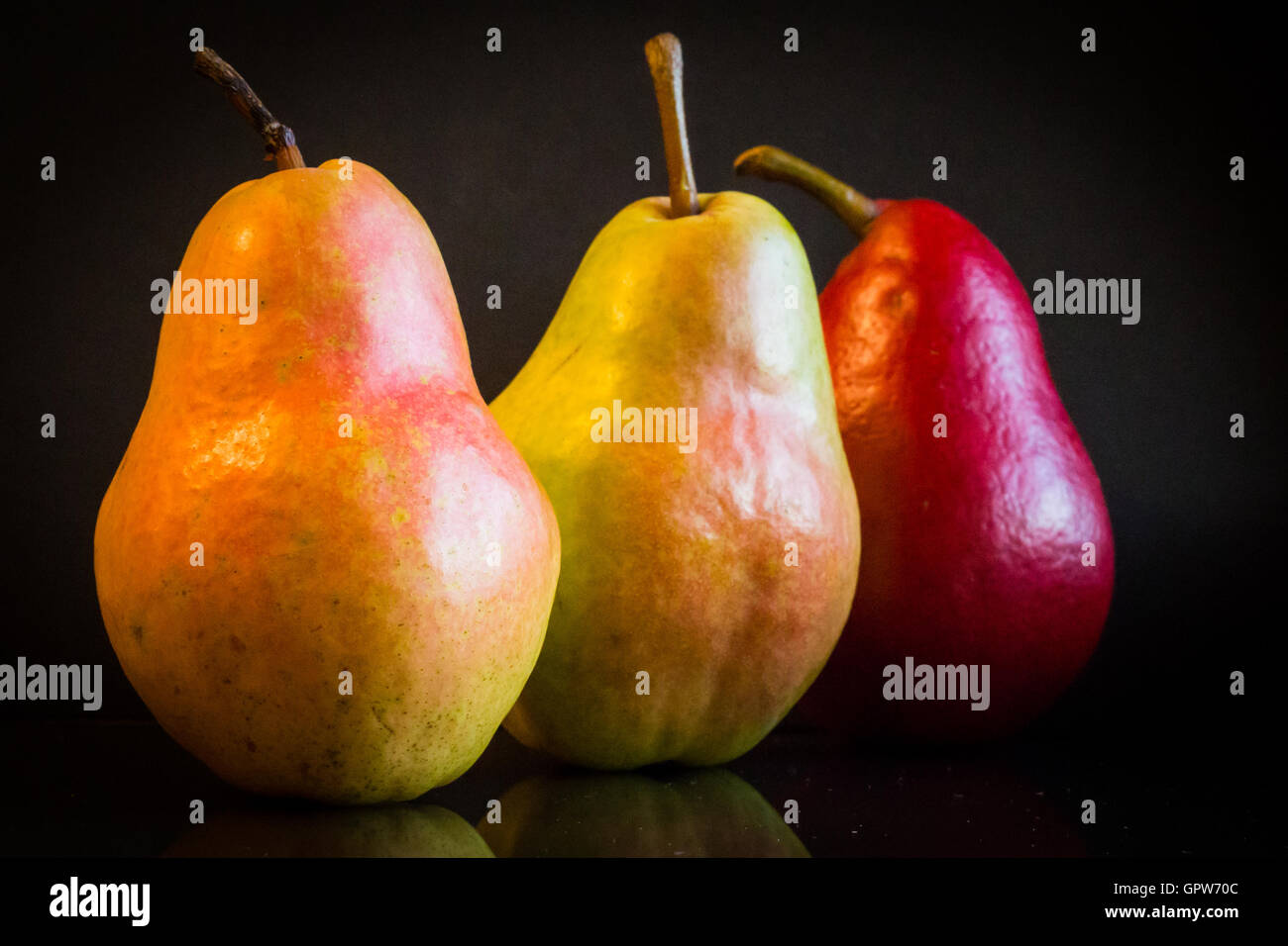 A collection of three different varieties of pears against a black ...