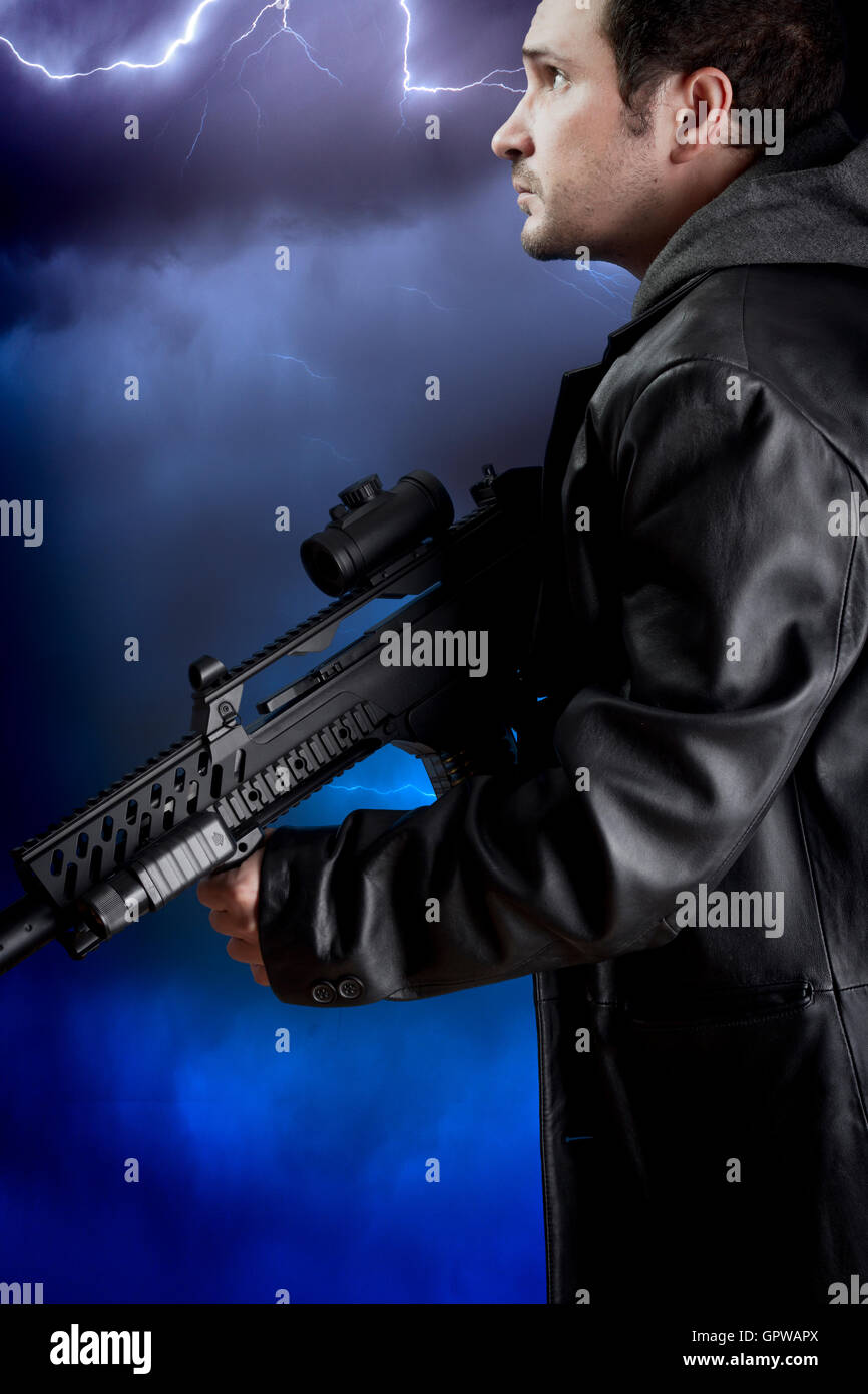 Man with long leather jacket and assault rifle over storm backgr Stock ...
