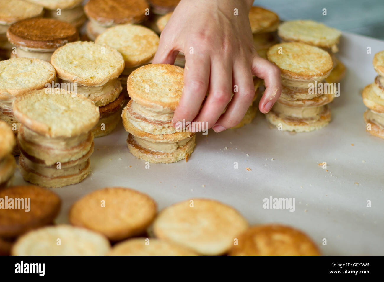 Hand touches cookies with cream Stock Photo - Alamy