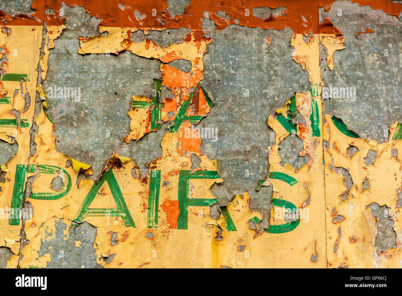 Handpainted letters of a shop signboard faded, peeling and weathered ...