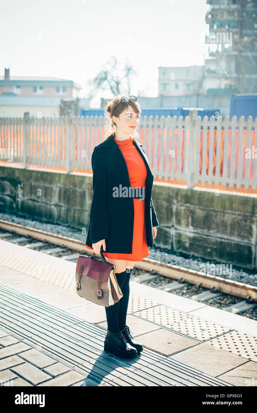 young beautiful red dressed vintage hipster woman outdoor in back light ...