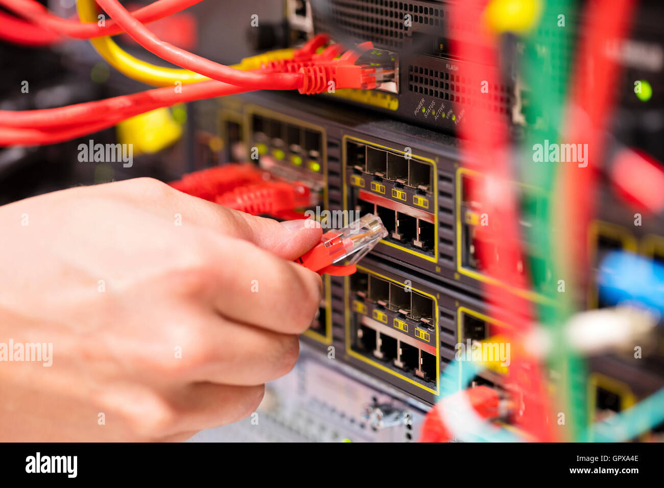 IT consultant connects a network cable into switch in datacenter Stock ...