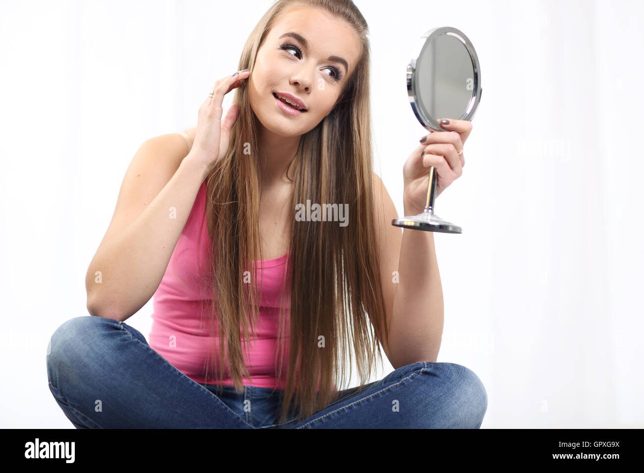 Girl sitting on the bed and holding a mirror Stock Photo - Alamy