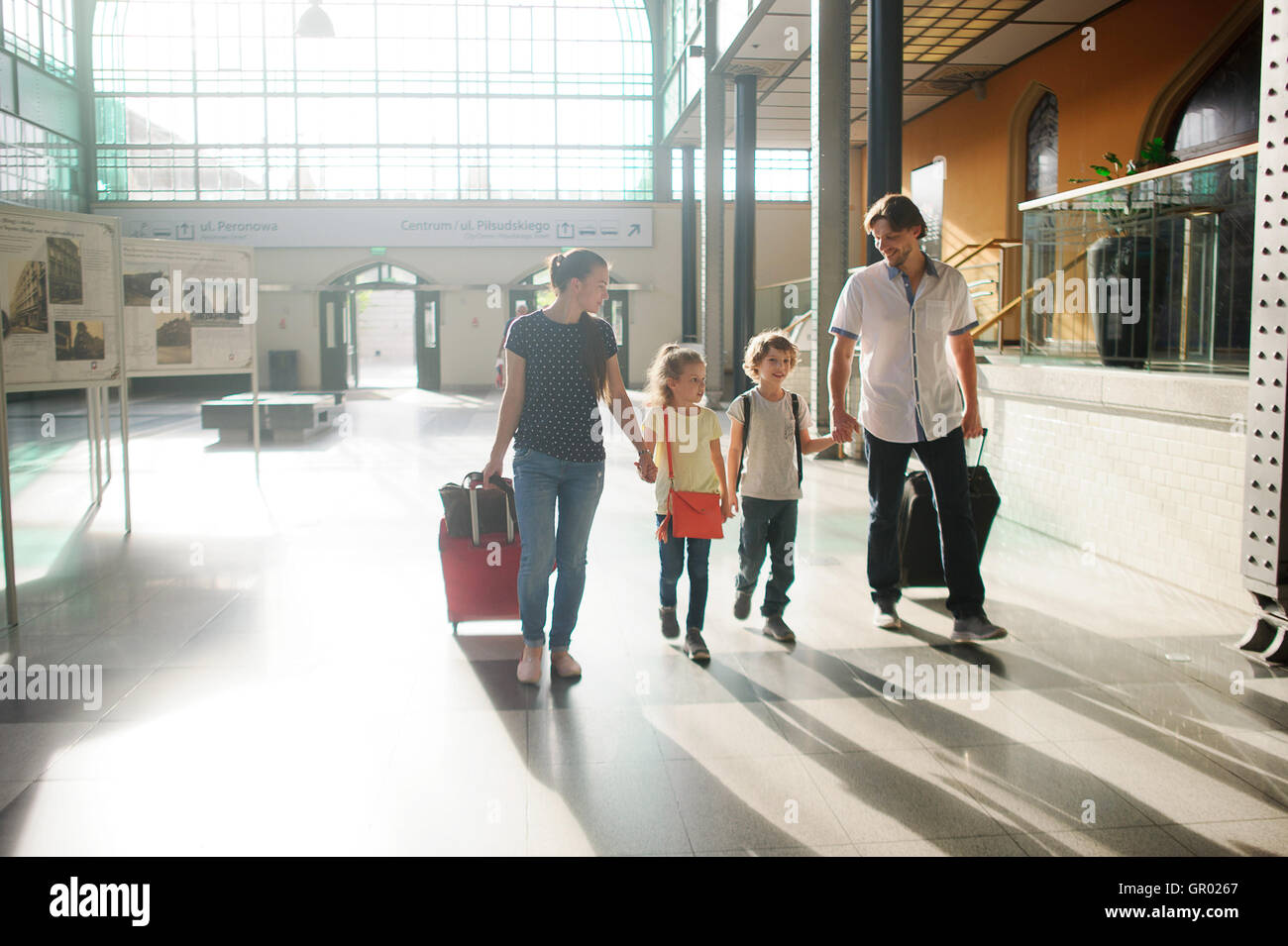 Young family in the waiting room at the station. Dad holds the hand of ...