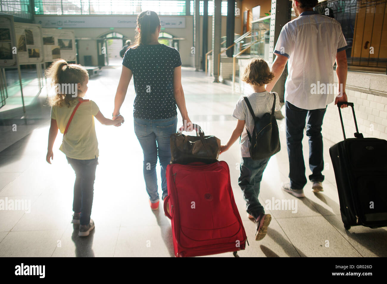 Young family in the waiting room at. the station. Dad holds the hand of ...