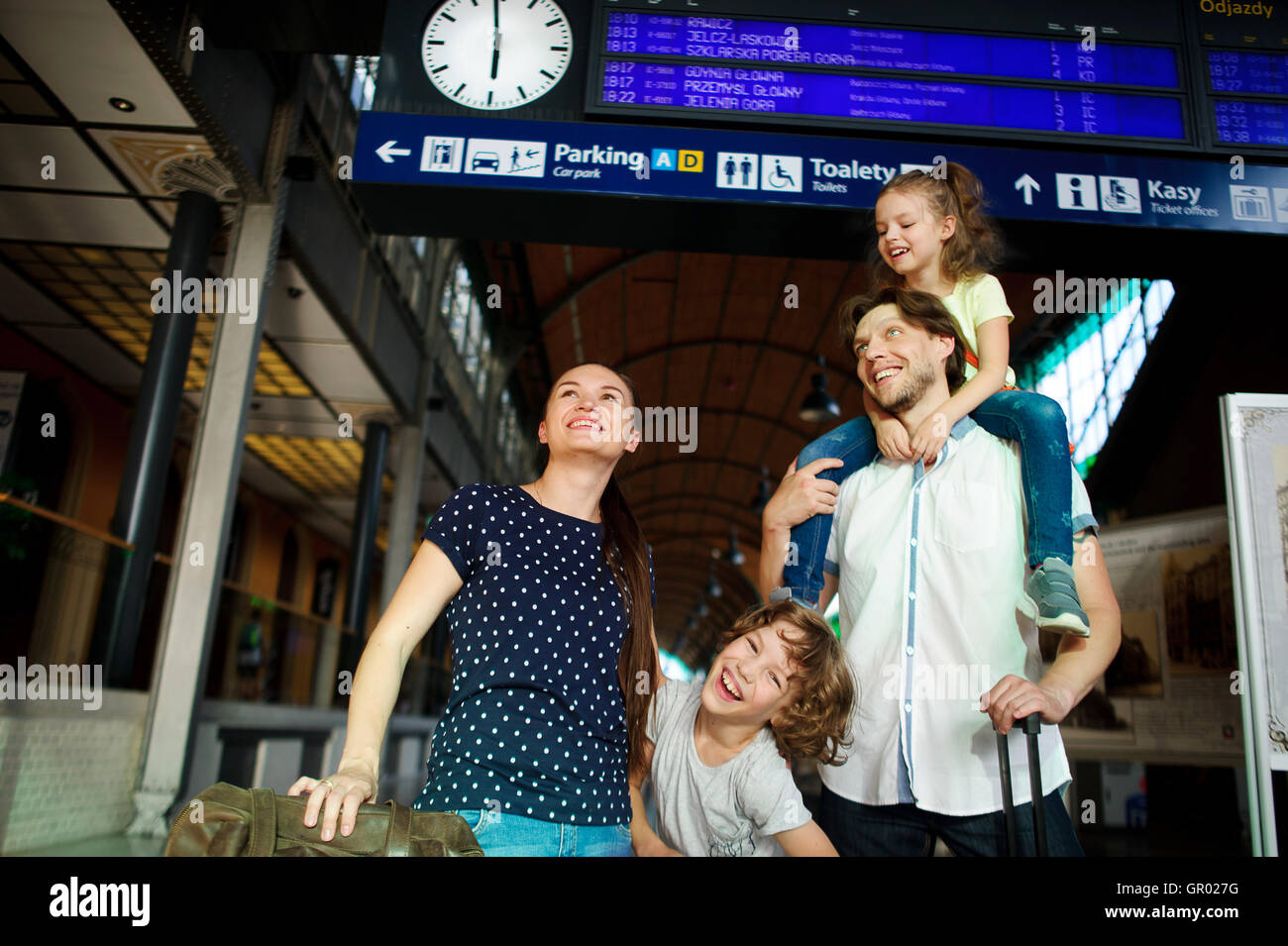 Cheerful young family at the train station. Dad, mom, son and daughter ...