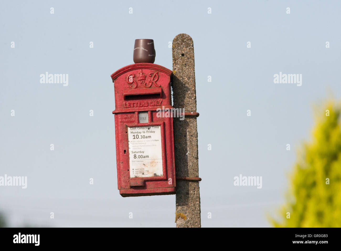 old letterbox attached to a pole in the countryside with a cup left on ...