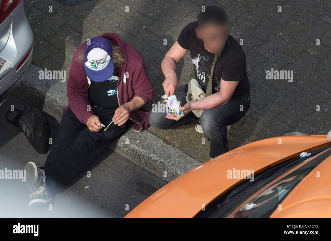 A drug addict preparing a crack pipe while a second man is looking out ...
