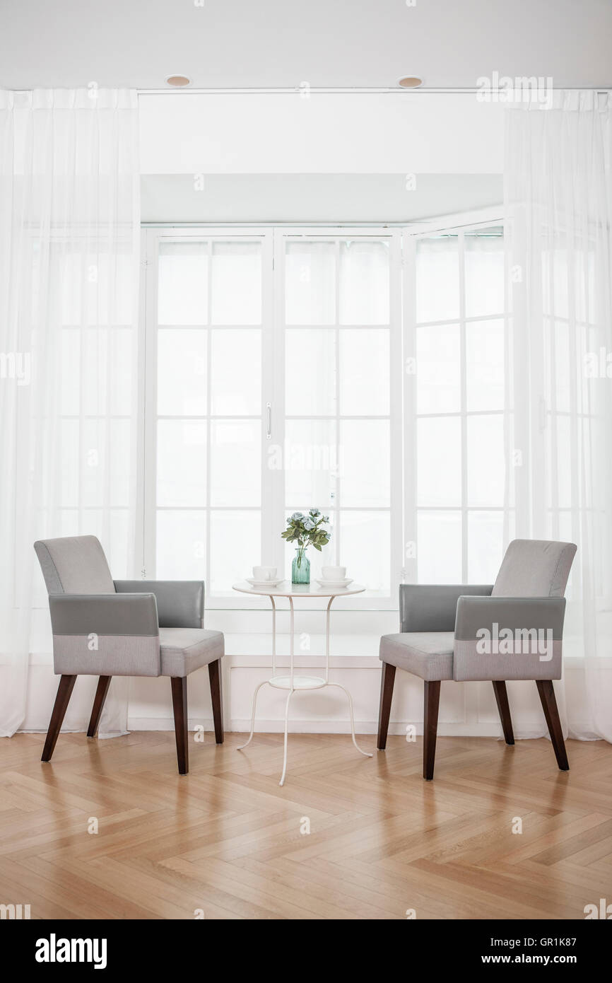 Interior with table and chairs against windows Stock Photo - Alamy