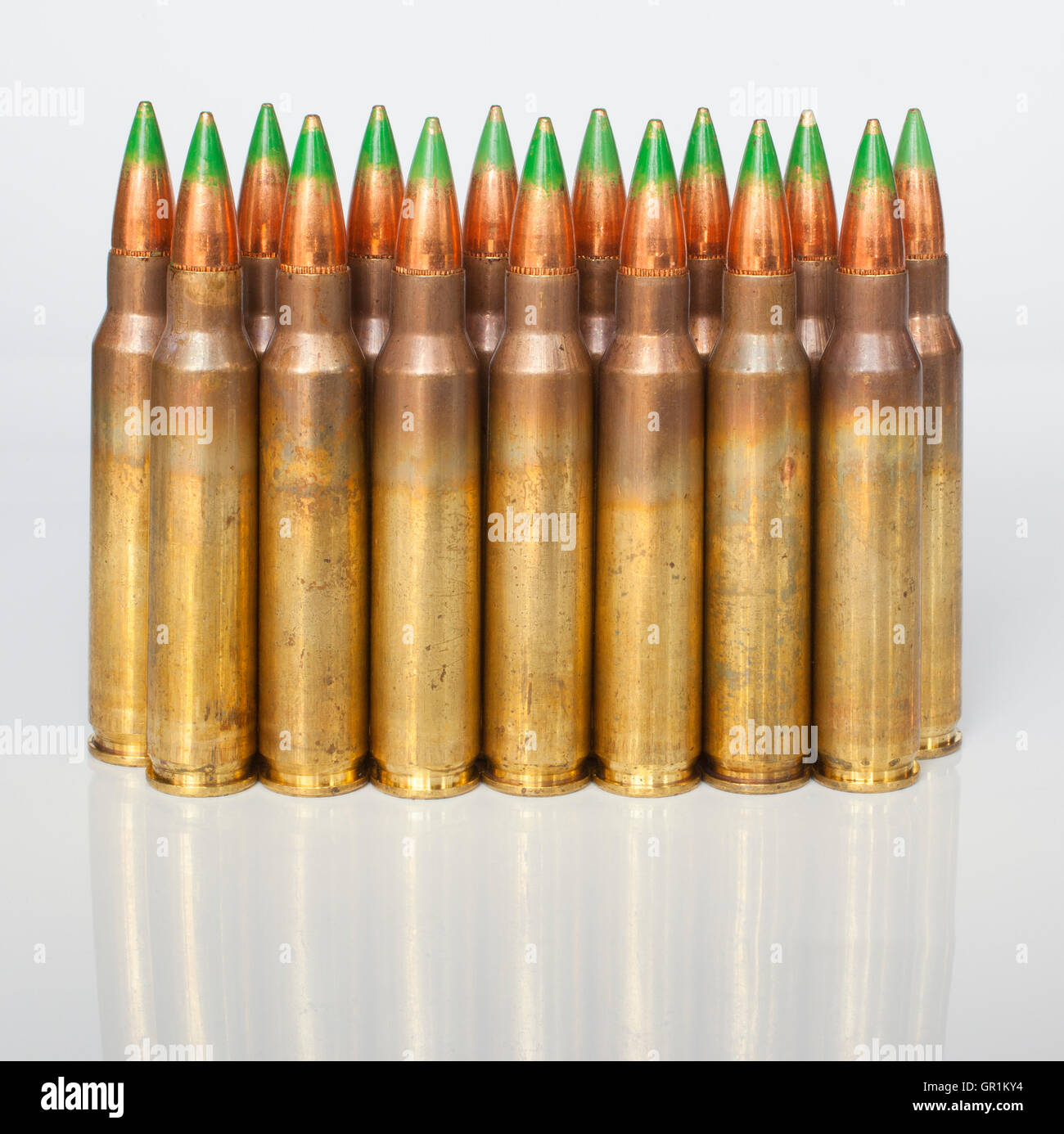 Cartridges loaded with bullets that have a green tip on a white ...
