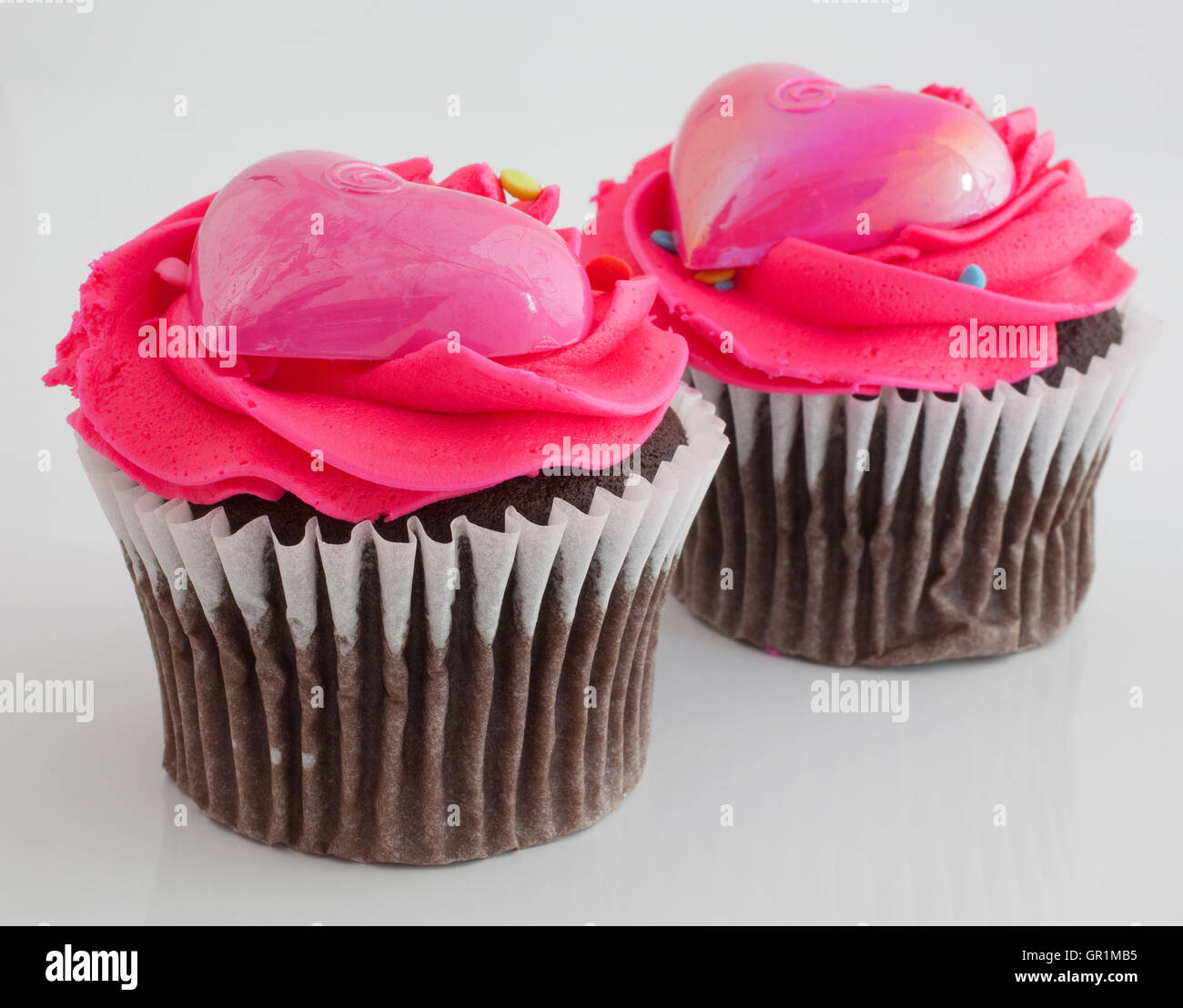 Two chocolate cupcakes that are covered with pink frosting Stock Photo ...