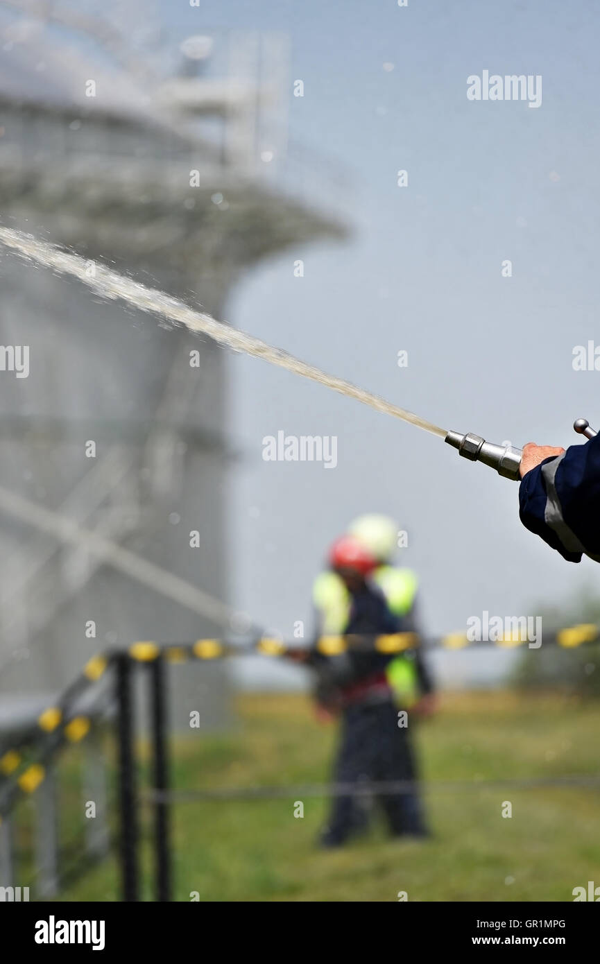 Firefighter holding high pressure water hose extinguishing a fire ...