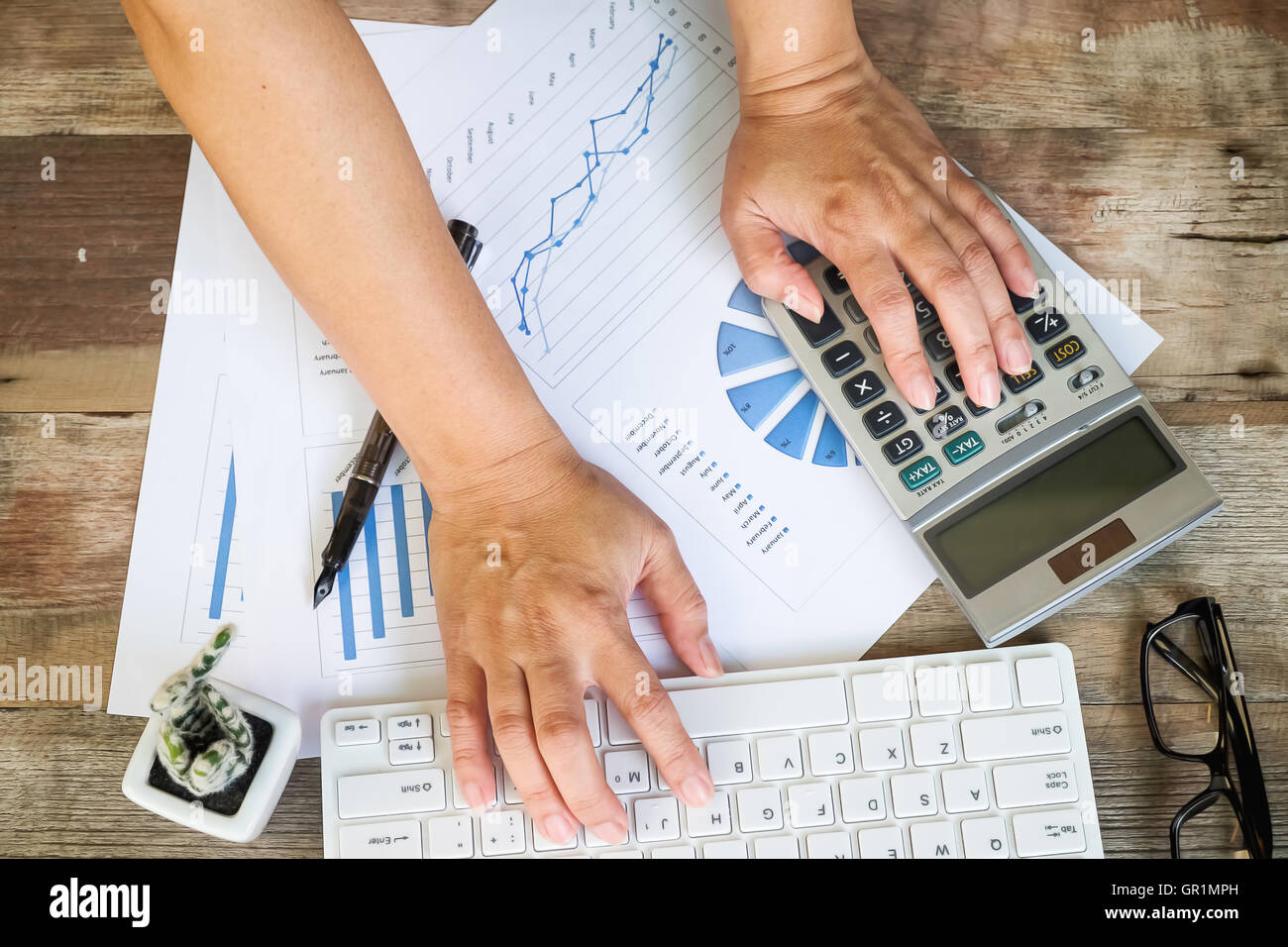 Asian Business woman using computer calculator to calculate the numbers ...