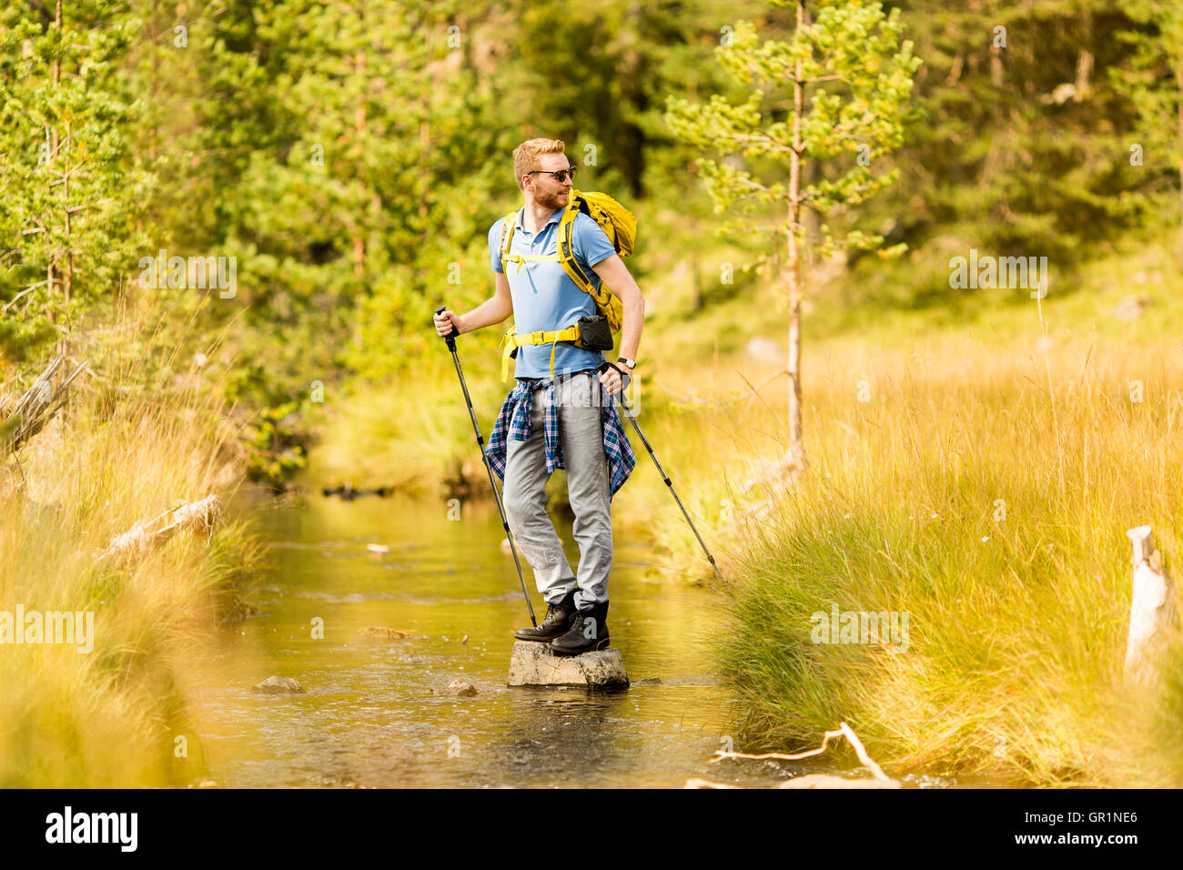 Young man crosses a mountain stream on a sunny day Stock Photo - Alamy