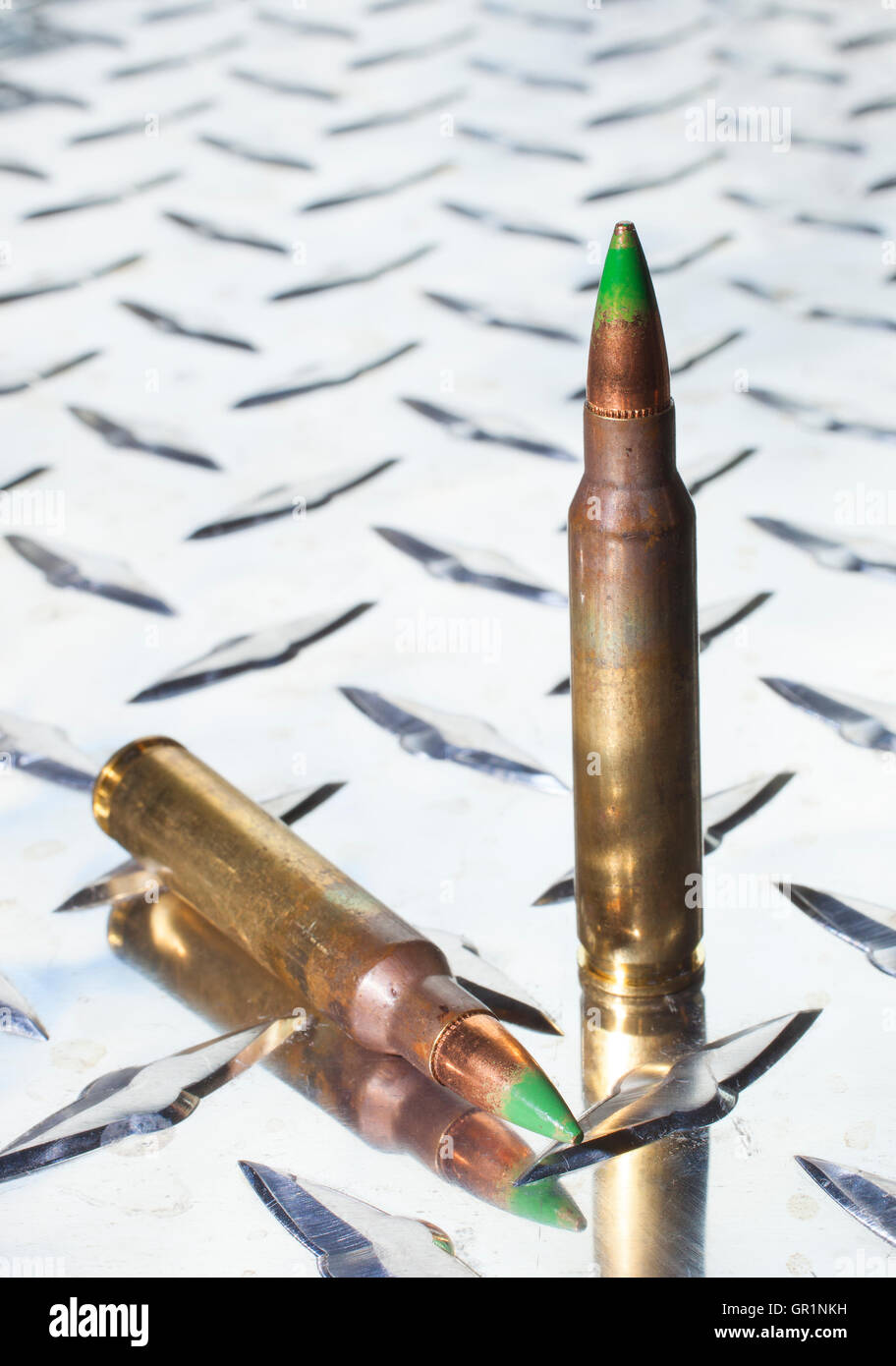Rifle cartridges with green tipped bullets on a piece or armor plated ...