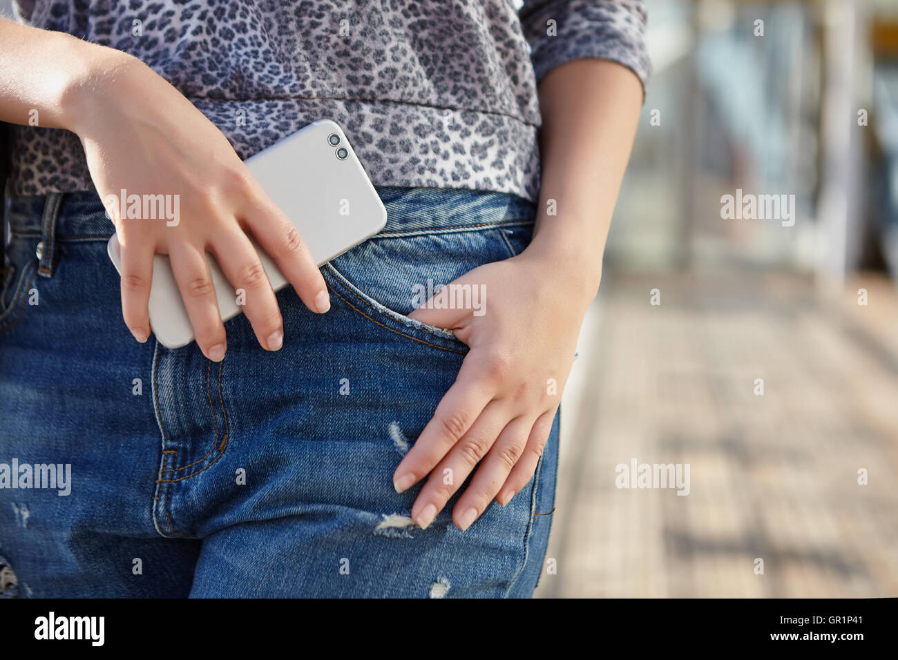 Young fashionable woman in blue jeans holding modern dual lens camera ...
