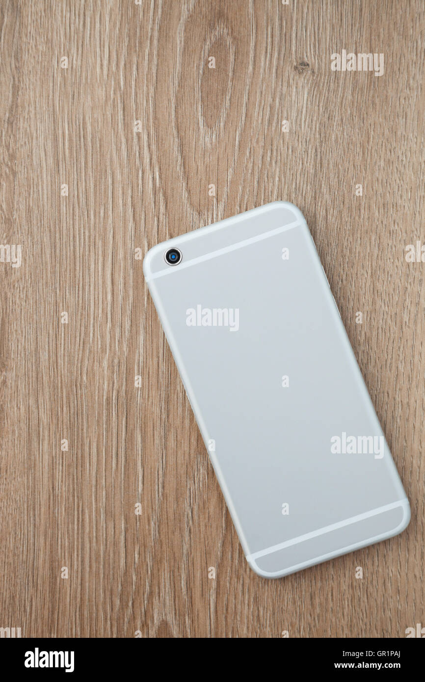 Mobile phone on wooden surface. Modern smartphone model, big silver ...