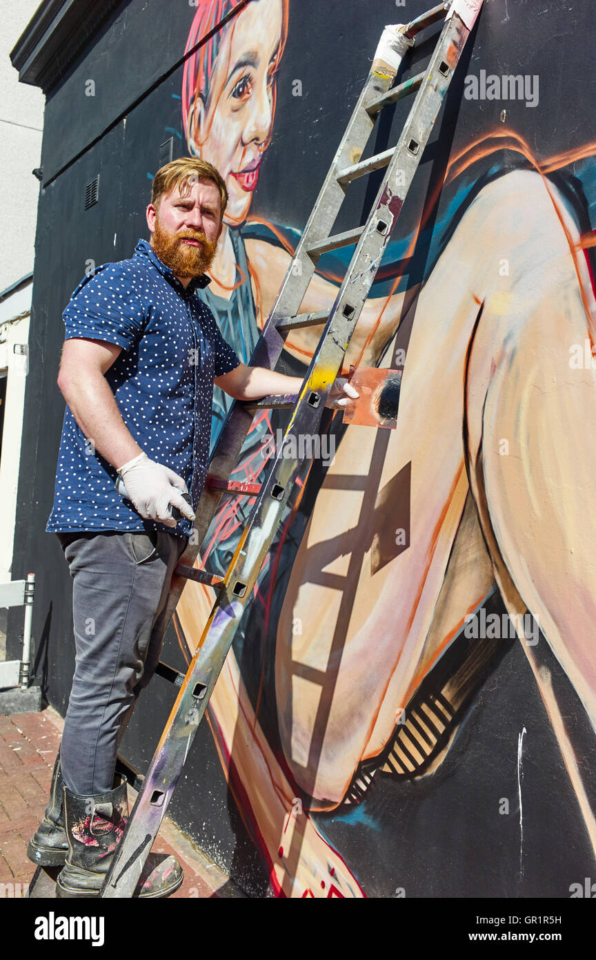 James Duggan, painting a wall mural at Market Hall, Douglas, Isle of ...