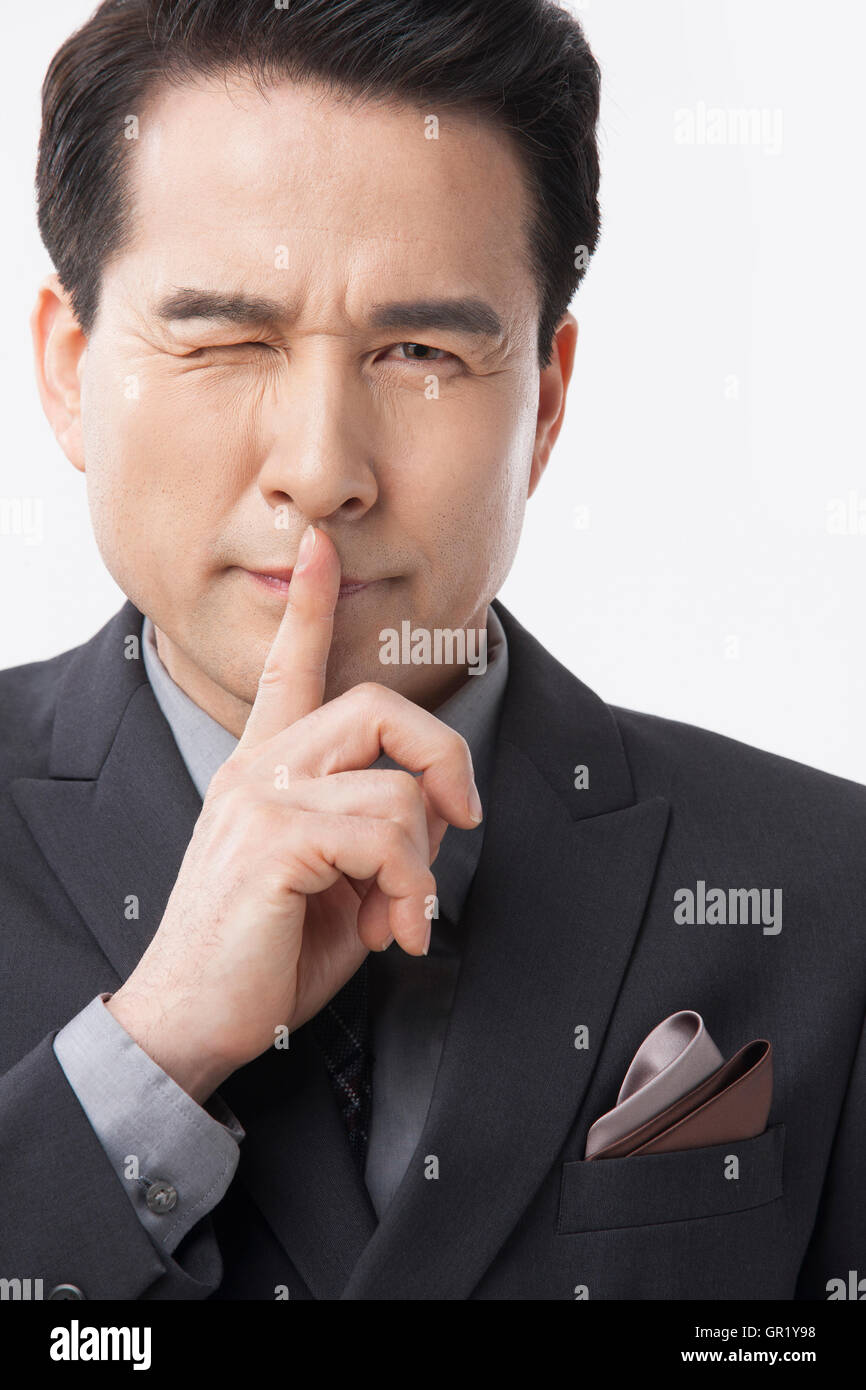Portrait of middle aged businessman winking with hush sign Stock Photo ...