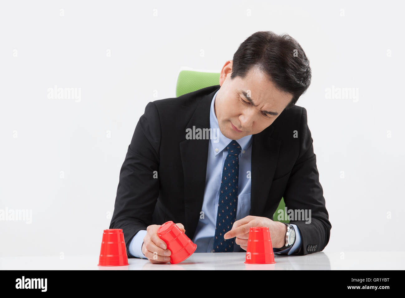 Portrait of middle aged businessman holding a cup among three frowning ...