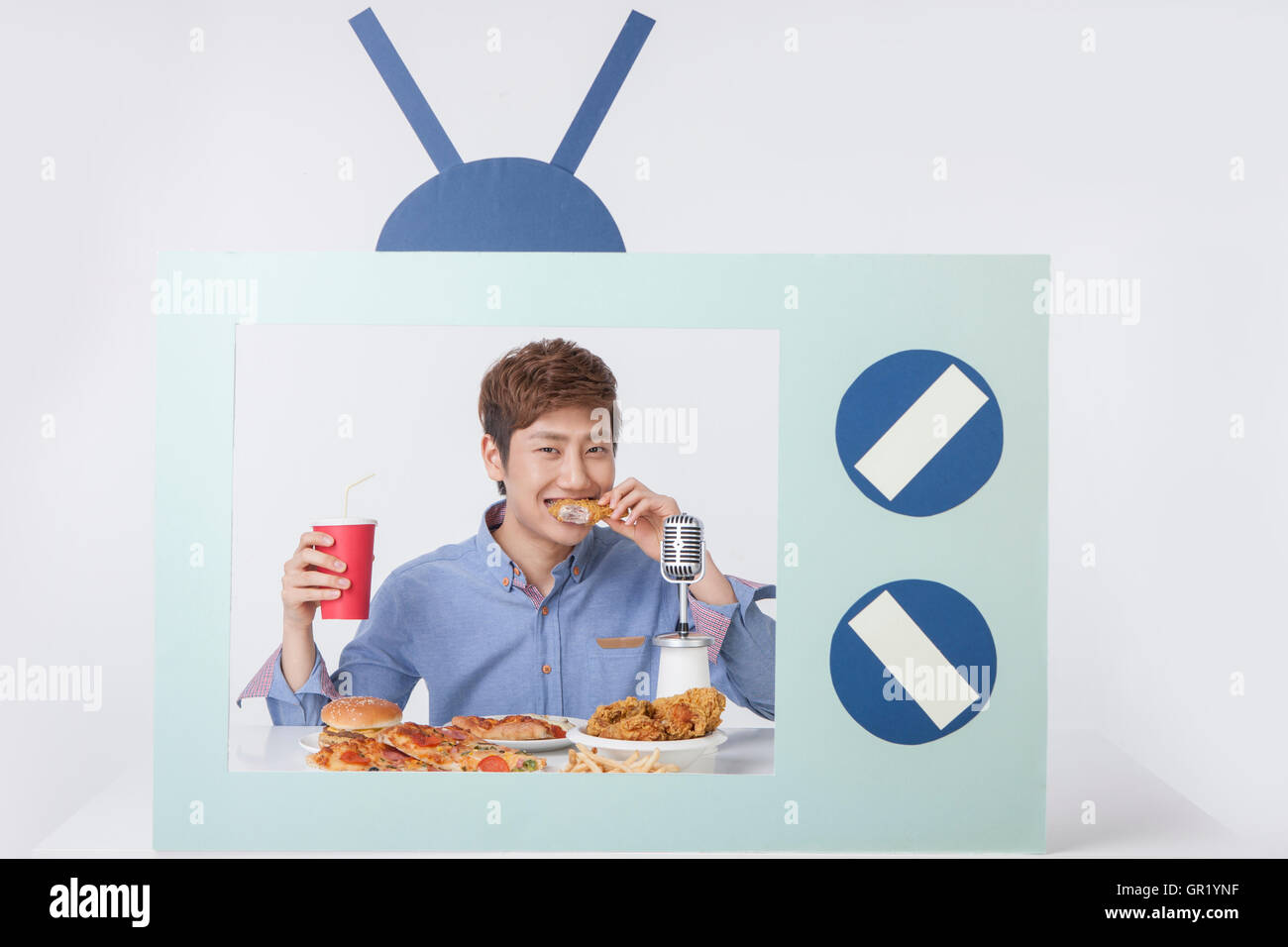 Portrait of young smiling man eating fast food on television Stock ...