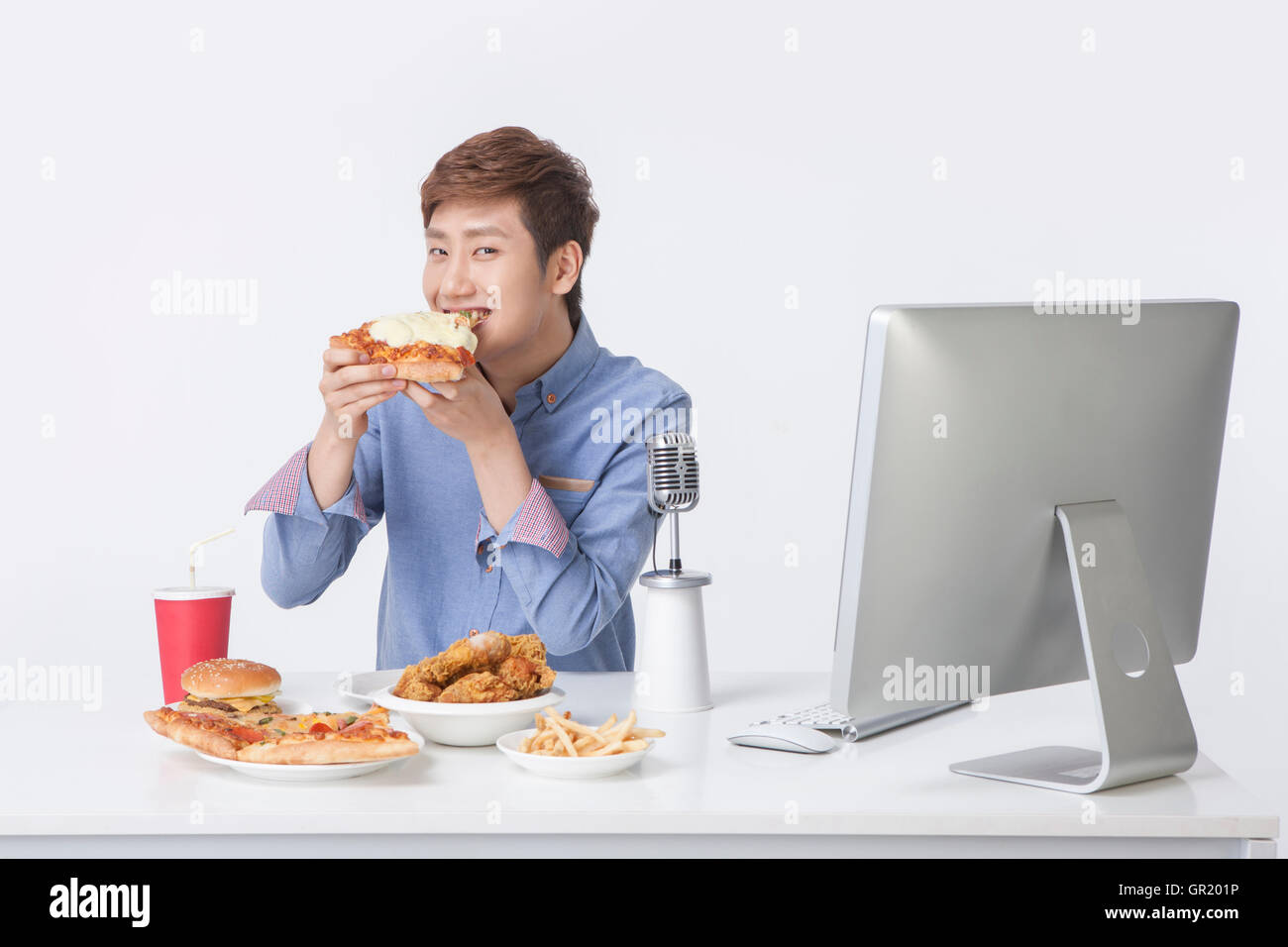 Portrait of young smiling man eating fast food during broadcasting ...