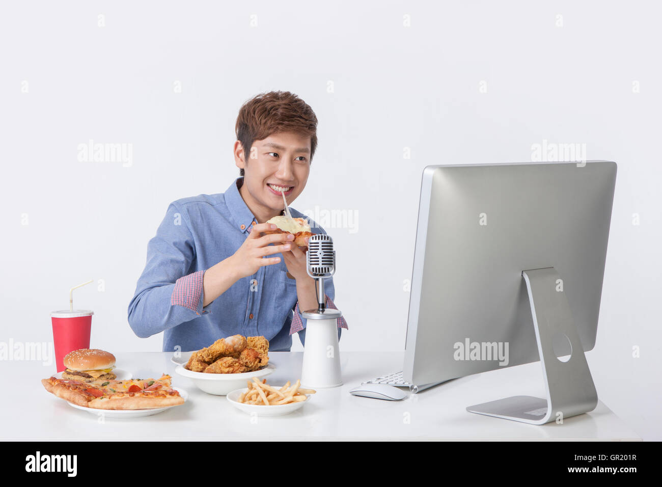Portrait of young smiling man eating fast food during broadcasting ...