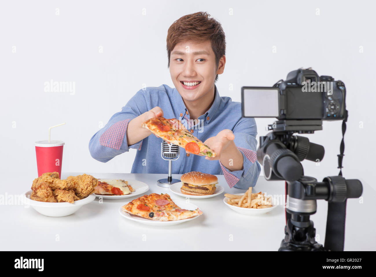 Portrait of young smiling man holding pizza in front of video camera ...