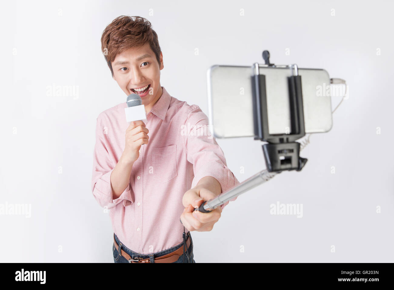 Young smiling man with microphone and selfie stick Stock Photo - Alamy