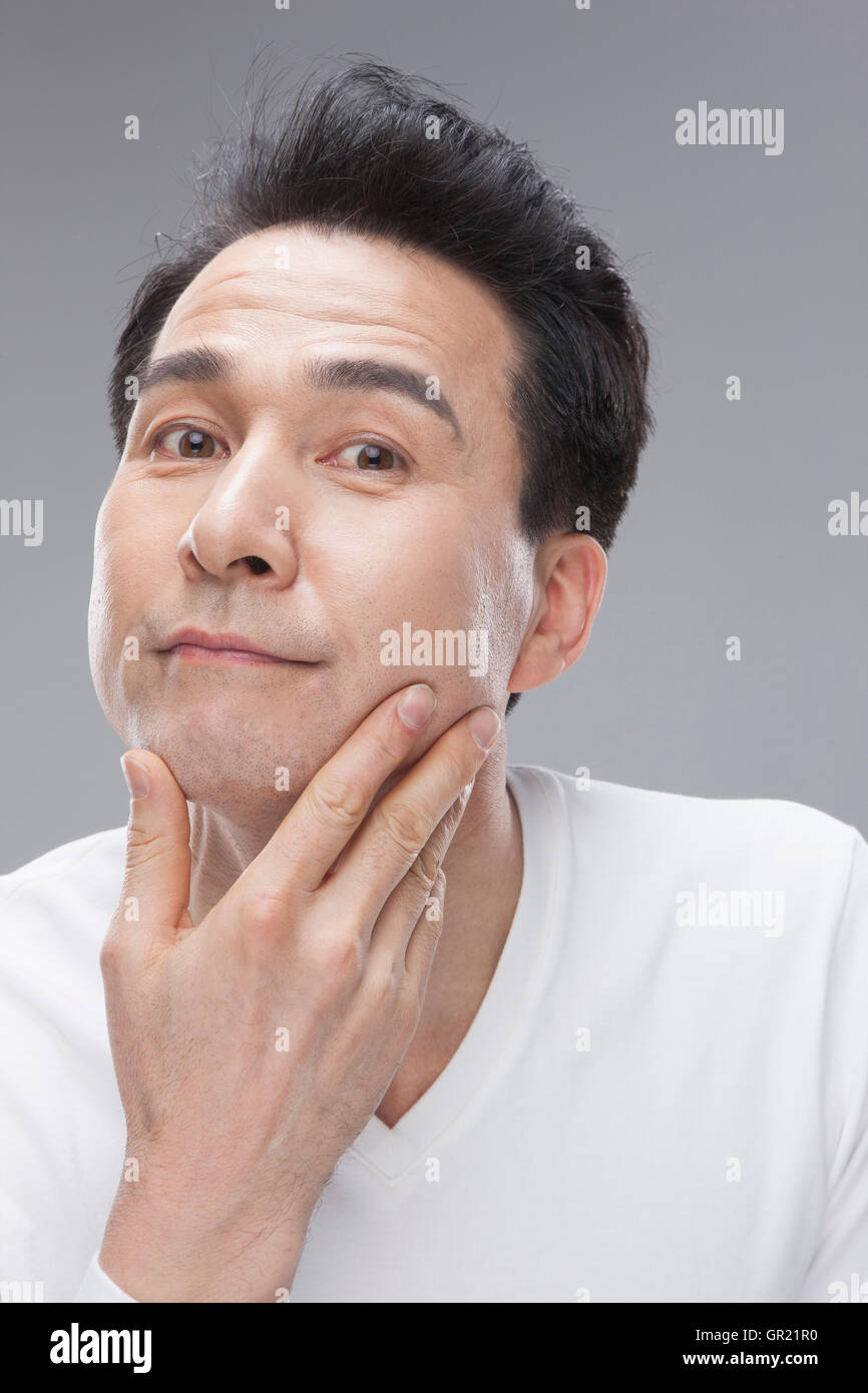 Middle aged man touching face Stock Photo - Alamy