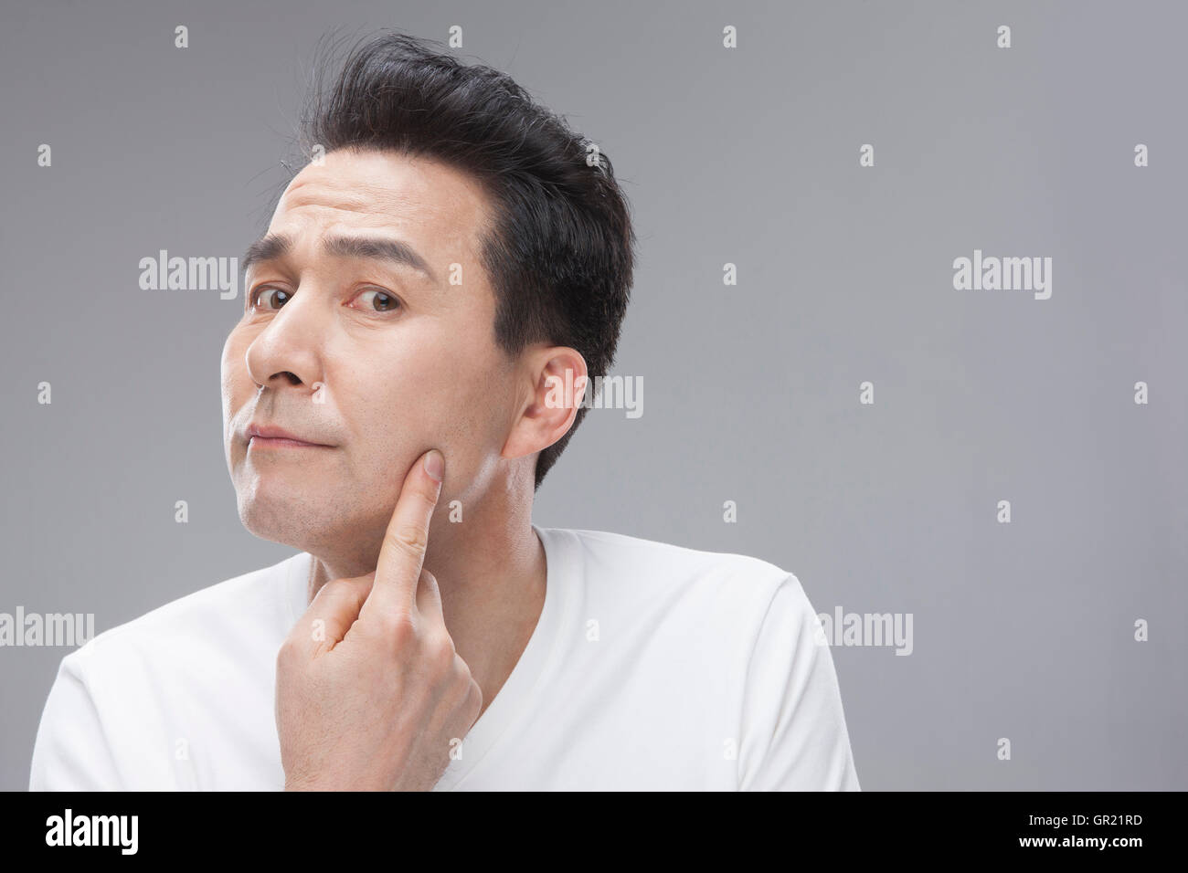 Middle aged man touching face Stock Photo - Alamy