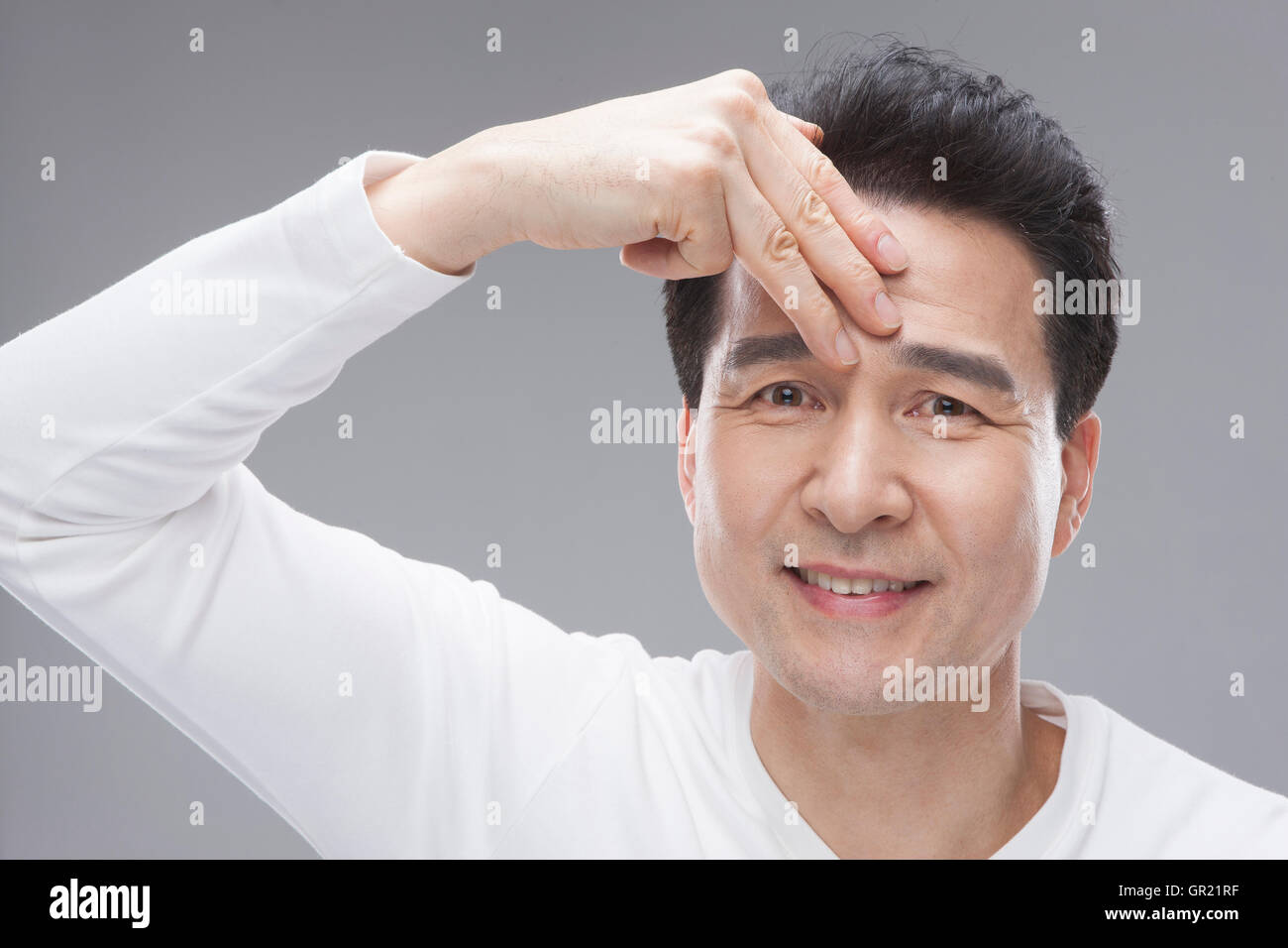 Middle aged man touching face Stock Photo - Alamy