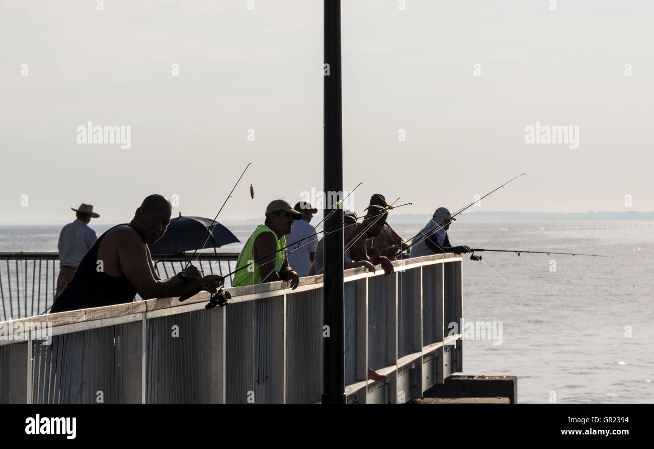 Fishermen with rods fishing from the end of a pier at sunset Stock ...