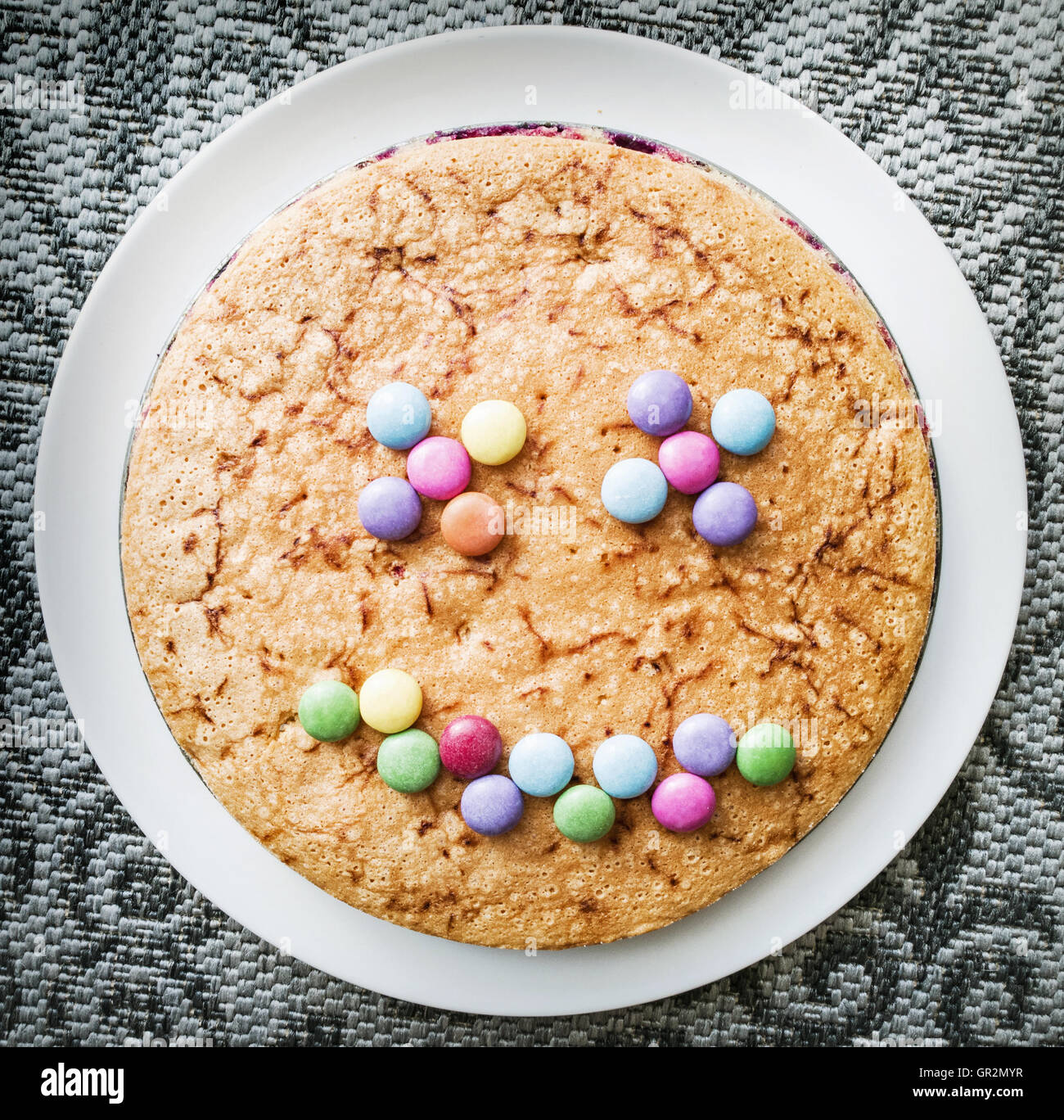 Tasty cake with colorful smarties in funny face shape. Festive sweet ...