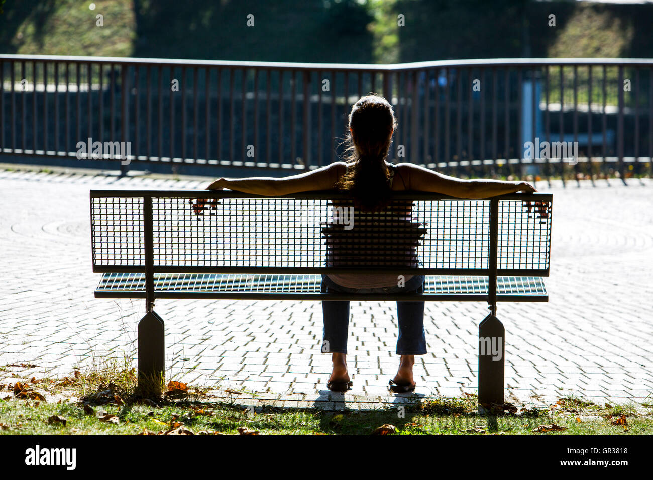 Young woman relaxed, relaxing on a park bench in the sun Stock Photo ...