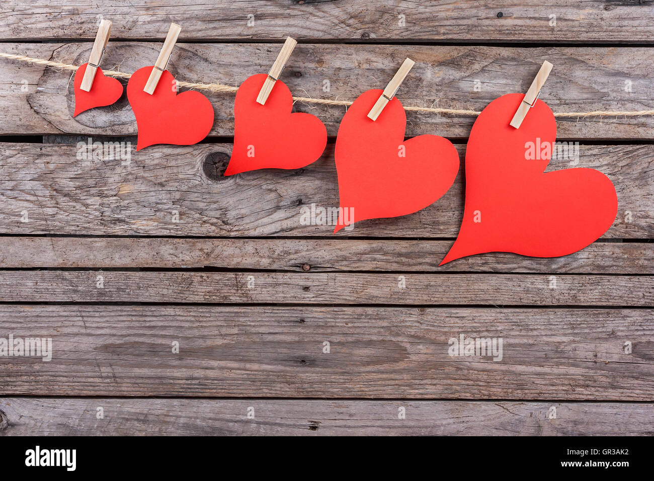 Five paper hearts hanging from a rope with wooden background Stock ...