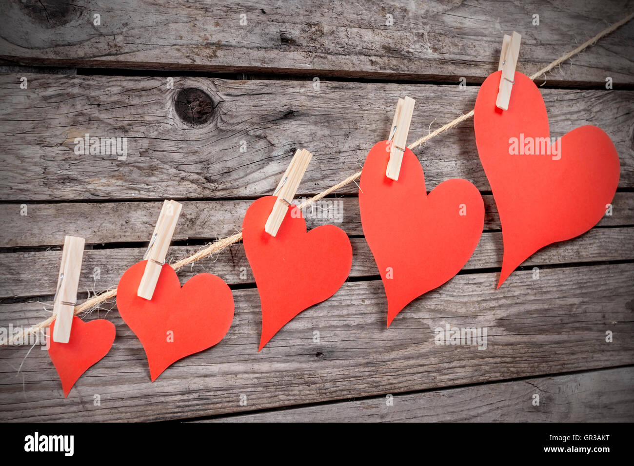 Five paper hearts hanging from a rope with wooden background Stock ...