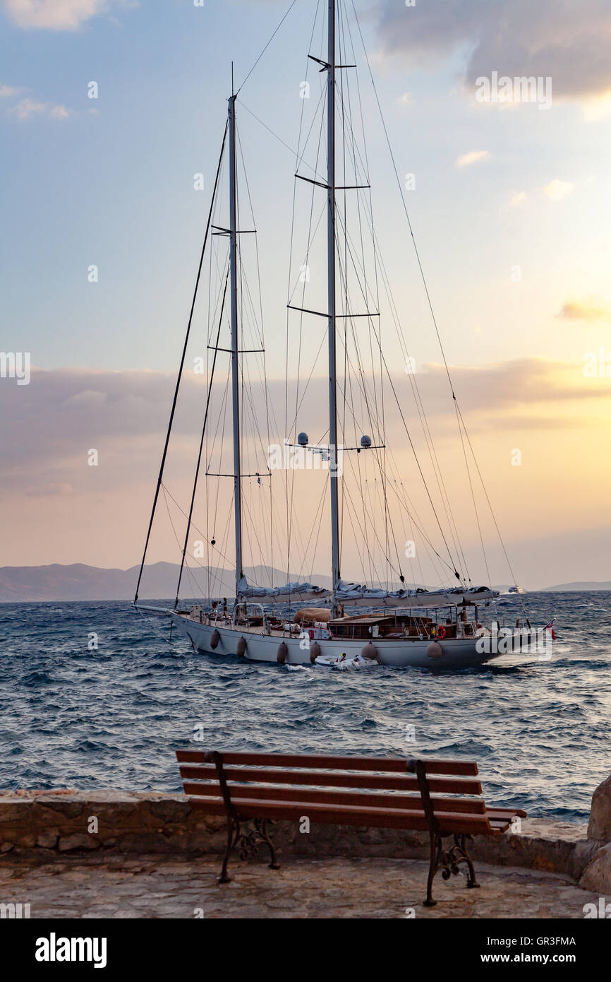 A sailing ship is passing in Hydra with a bench in foreground Stock ...